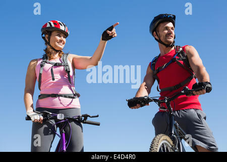 Fit cyclist couple standing at the summit smiling at camera Stock Photo ...