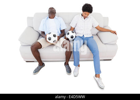 Distraught football fans sitting on the couch with balls Stock Photo ...