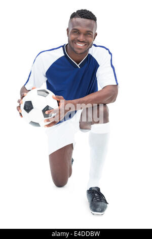 Happy football player in blue holding the ball Stock Photo - Alamy