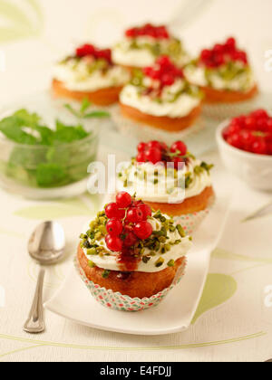 close up of cake decorated with currants and mint leaves near cup of ...