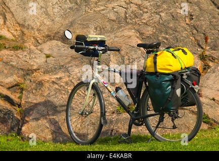 Red touring bicycle loaded with heavy gear in four pannier bags stand ...