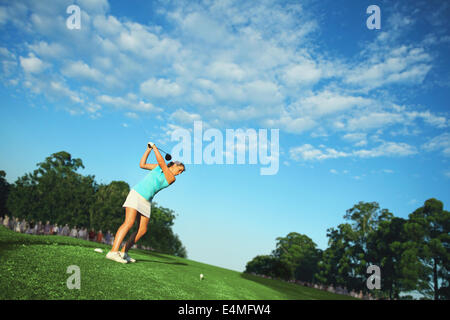 Female golf player teeing-off golf ball at beautiful golf course with ...