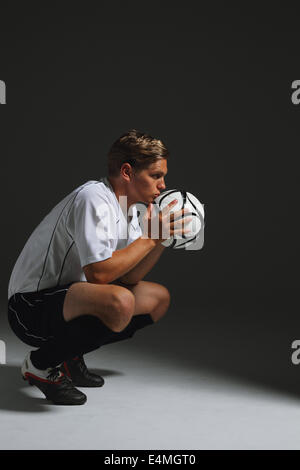 Soccer player crouching with ball side view Stock Photo - Alamy