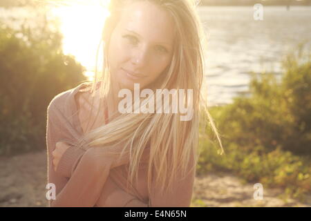 blond girl sitting near river against sun Stock Photo - Alamy