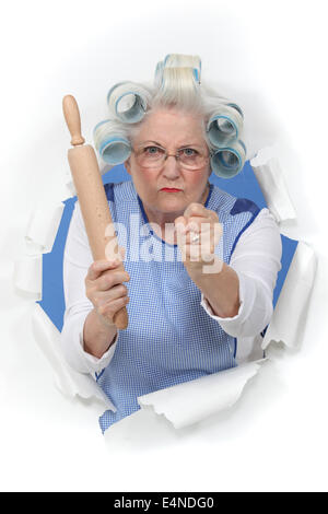 Emotional elderly woman brandishing a kitchen knife in her hand with a ...
