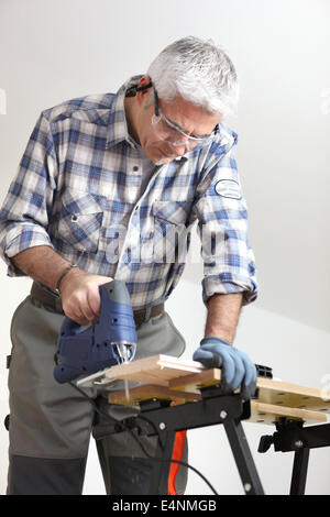 Woodworking - man using electric jigsaw to cut pine timber Stock Photo ...