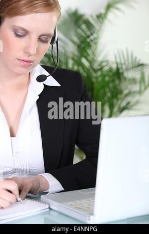 Receptionist or call centre operator taking a telephone call on a ...