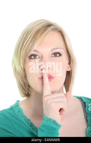 Beautiful young woman hushing with finger on lips. Studio shot with ...