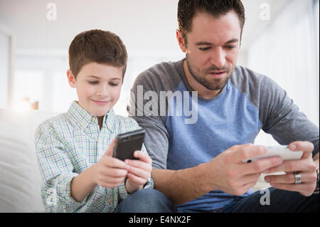 Father and son using mobile phones sitting on dining table Stock Photo ...
