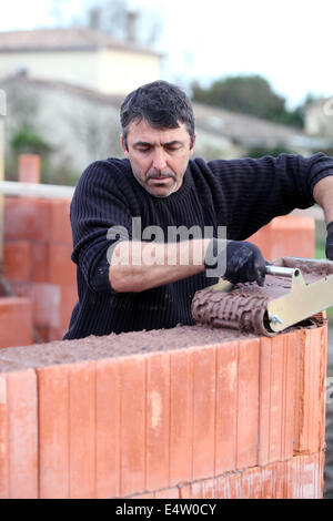 Mason checking the level of a brick wall, Bricklayer with personal ...