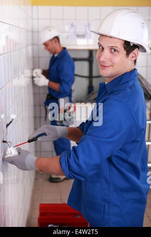 Electrical team wiring wall sockets Stock Photo - Alamy