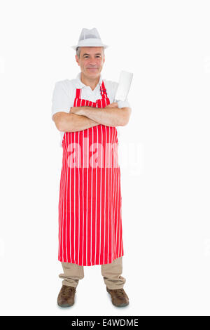 Smiling mature butcher in white overall slicing jamon in delicatessen ...