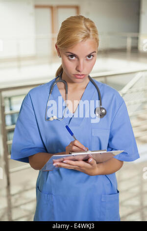 Serious nurse writing on clipboard Stock Photo - Alamy