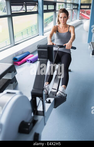 Brunette woman training on row machine Stock Photo - Alamy