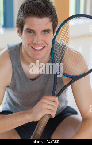 Close up of man holding tennis racket on clay court. On court is sunset ...