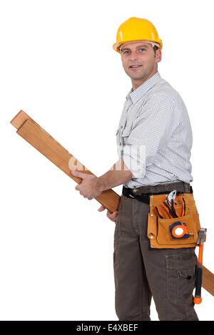Man builder carrying wooden planks in construction site Stock Photo - Alamy