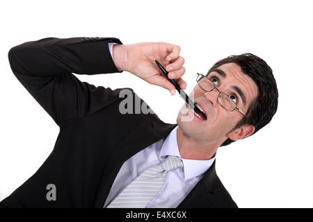 Businessman chewing his pen Stock Photo - Alamy