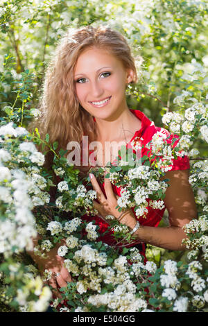 Young woman touching blooming red flowers against building Stock Photo ...