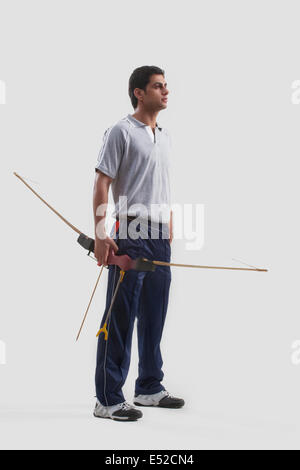 Full length of male archer with bow and arrow against gray background ...