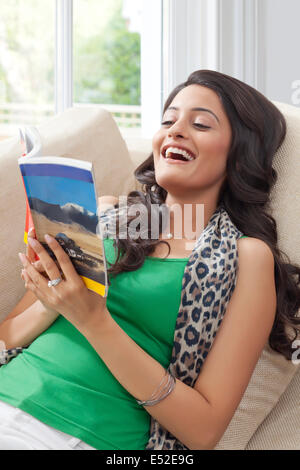 Woman laughing while reading a book Stock Photo - Alamy
