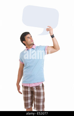 Young man holding speech bubble with question mark on white background ...