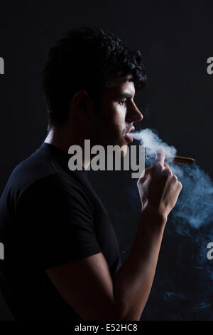 A vertical shot of a young man smoking a cigarette and wearing ...