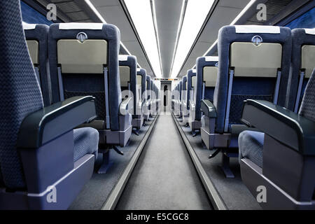 Row of empty seats on a train carriage with red grip handles. NI ...
