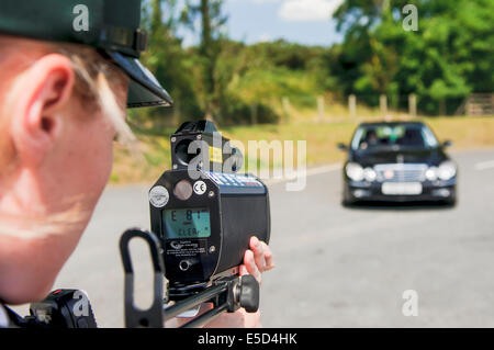 Female police officer uses a laser speed gun to detect a speeding car ...