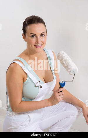 Young white woman painter holding paintbrush standing at the canvas ...