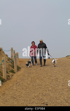 Walkers and dog on Happisburgh beach. Norfolk. Tide encroaches and will ...