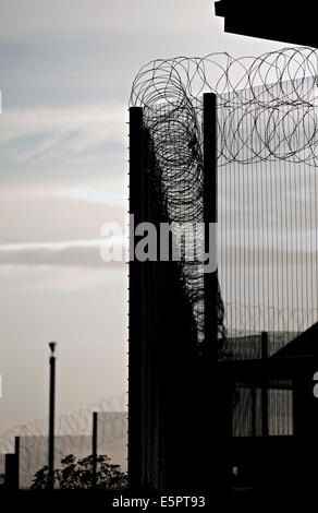 Security fencing, razor wire and CCTV cameras around the perimeter of a ...