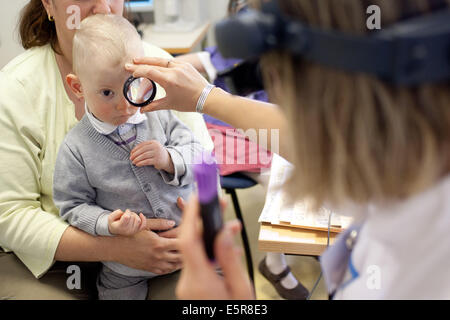 Ophthalmologist examining the interior of the eye of a baby with an ...