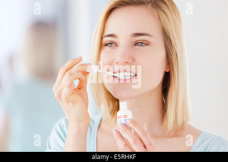Woman applying a bleaching gel on her teeth Stock Photo - Alamy