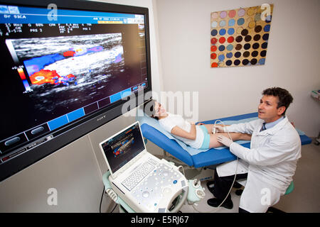 Woman undergoing a Doppler ultrasound (angiodynography) scan of the ...