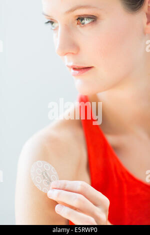 Woman applying a patch in prevention of angina pectoris Stock Photo - Alamy