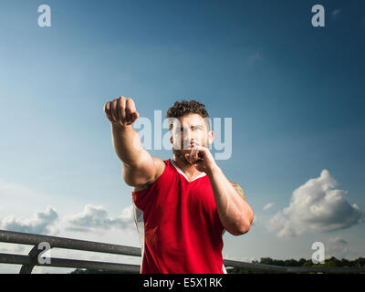 Portrait of muscular male boxer posing in boxing stance against grid ...