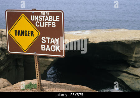 Unstable cliff edge sign warns against the danger of falling rocks and ...