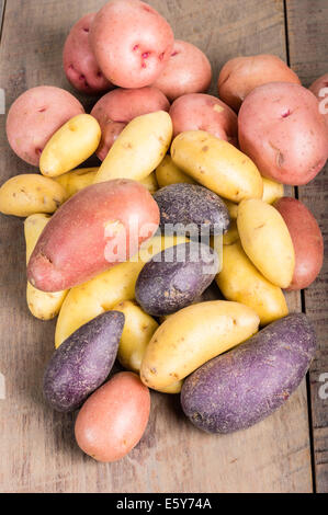 Fresh red potatoes on wooden board with garlic oil bottle in background ...