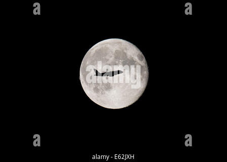 An airplane flying across a full moon Stock Photo - Alamy
