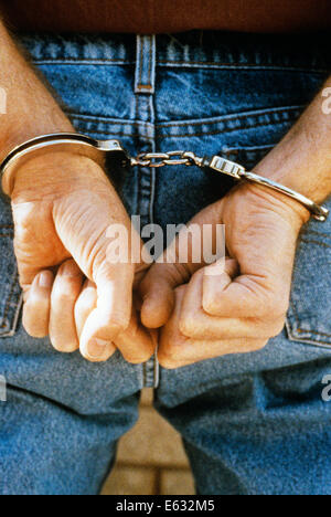 Close-up of handcuffed male suspect in dimly lit interrogation room ...