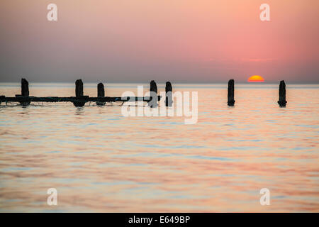 Israel, Beit Yanai, Poles in the sea the remains of a wharf at sunset ...