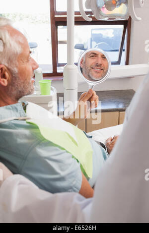 Pleased male admiring his reflection in mirror in aesthetic clinic ...