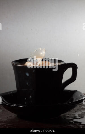 Tea being dropped in to a cup to make a splash Stock Photo - Alamy