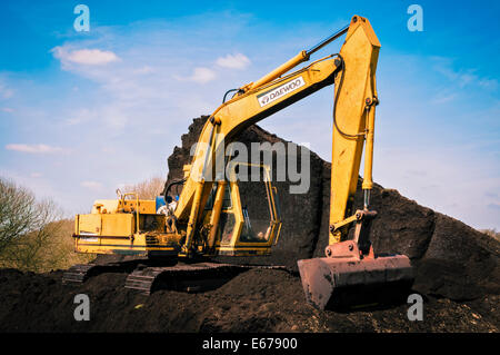 tracked excavator bucket digging peat for the preparation of land ...