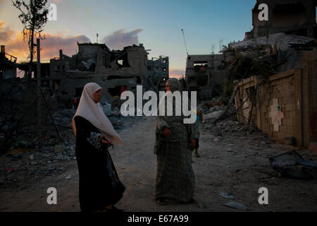 Palestinians walk past destroyed buildings in the northern Gaza Strip ...
