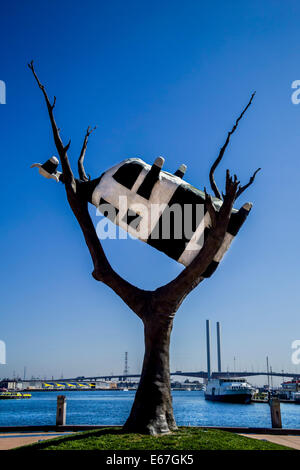 Cow up a tree upside down black & white cow sculpture against deep blue ...