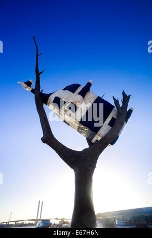 Cow up a tree upside down black & white cow sculpture against deep blue ...