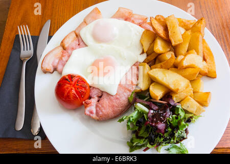 Meal of gammon rasher fried egg potato chips pineapple peas and English ...