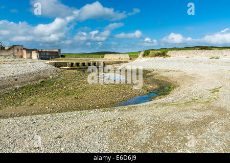 Bridge structure and other buildings viewed from beach at Cemlyn Bay ...