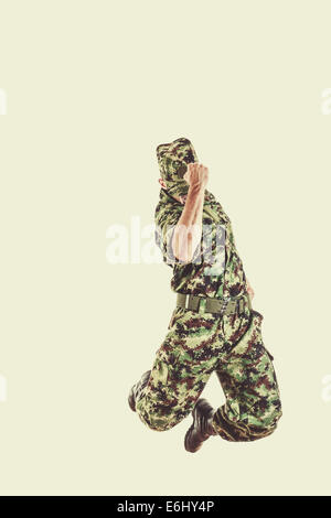 unknown soldier with hidden face in green camouflage uniform kicking ...